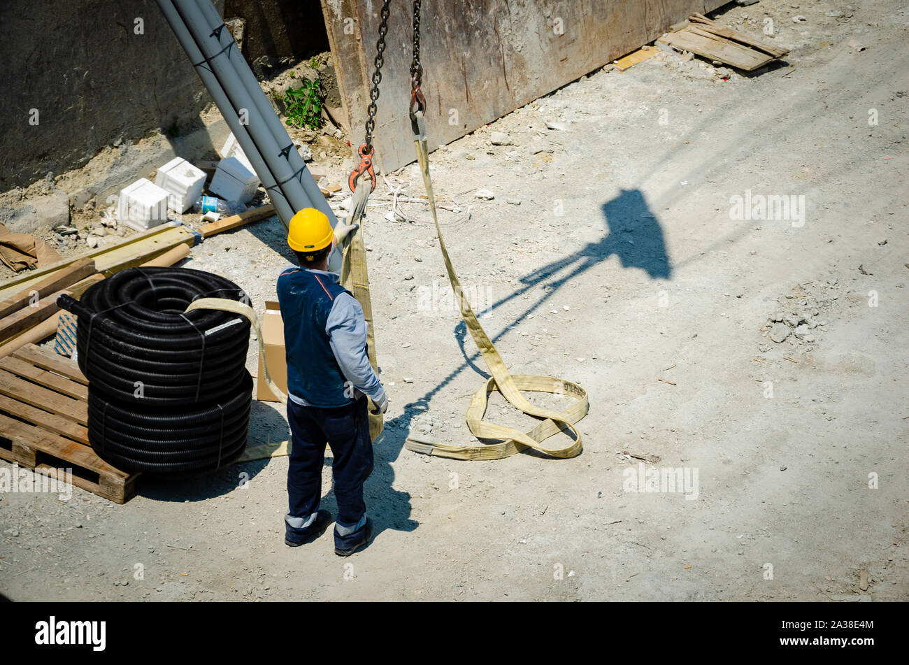 A worker man in helmet is ready to hang a Drain or corrugated pipe to ...