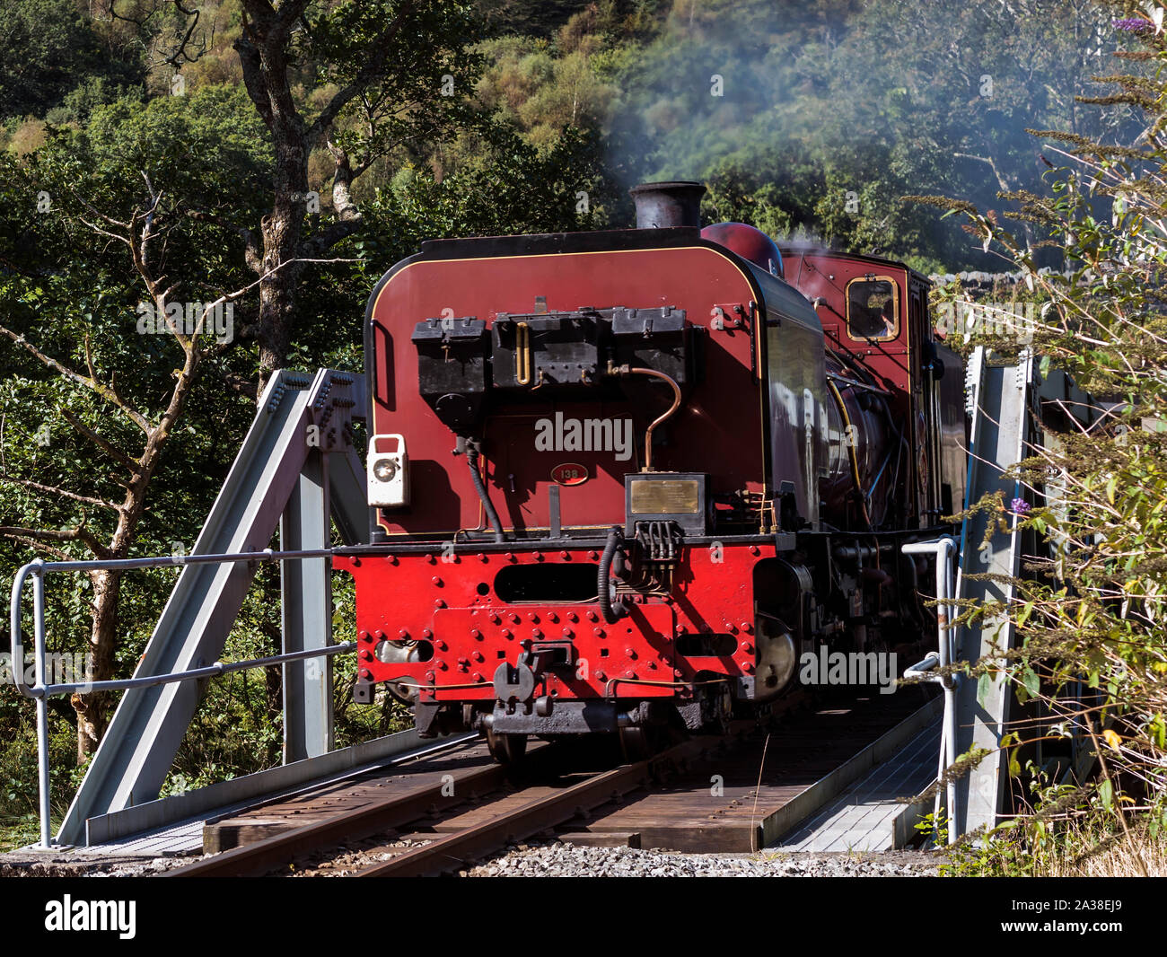 Dark red Welsh Highland Heritage Railway steam engine crossing metal ...