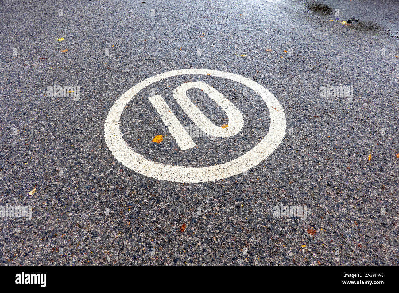 10 mile per hour speed limit sign painted in white on asphalt road ...