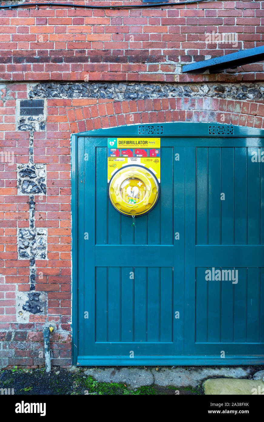 Life saving defibrillator machine mounted on green painted wooden door ...