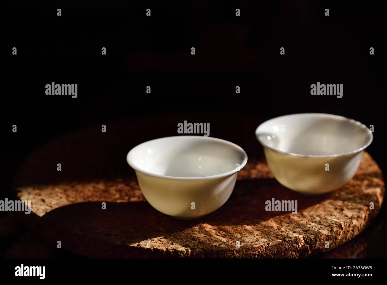 Close up of two empty small white chinese tea cups standing against a ...