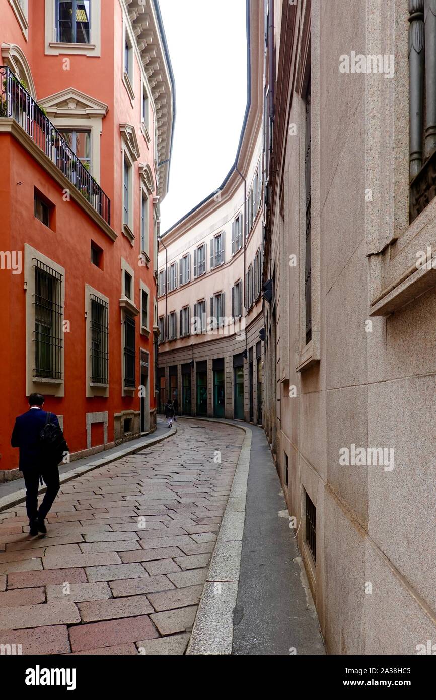 Two lone people walking on a bricked, curving, almost empty street, Via ...