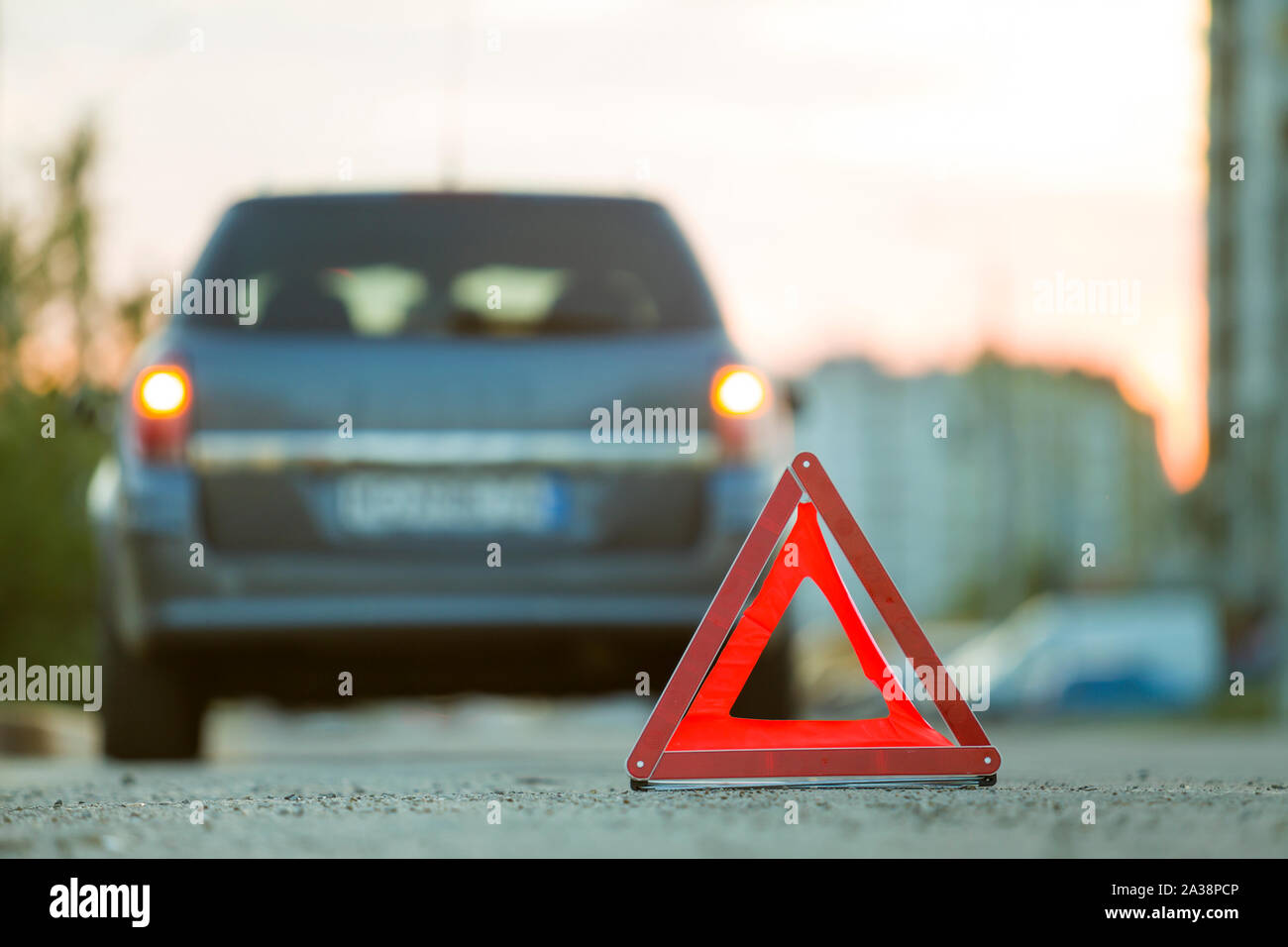 Red emergency triangle stop sign and broken car on a city street Stock ...