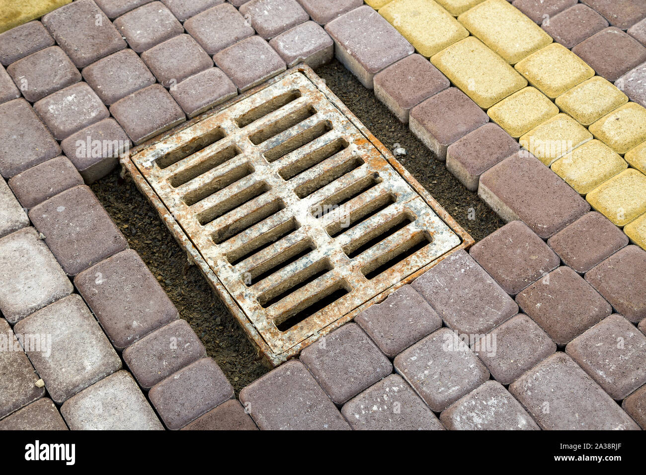Old rusted metal gutter for rain water on the stone paved sidewalk ...
