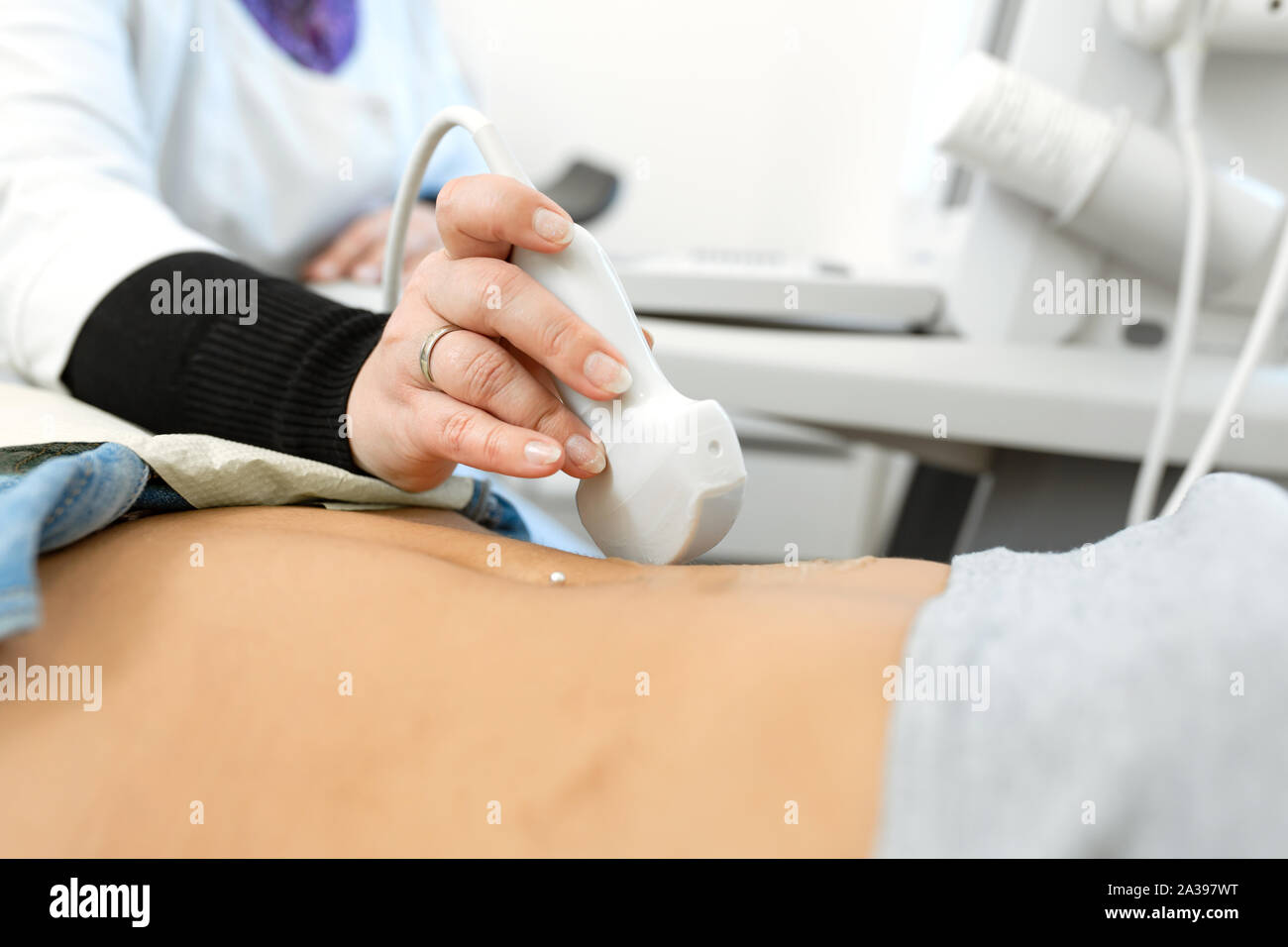 Close-up doctor conducts ultrasound diagnostics of the patients abdomen ...