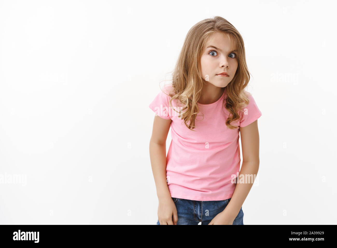 Intrigued smart, nosy and curious young little girl, peeking, frowning ...