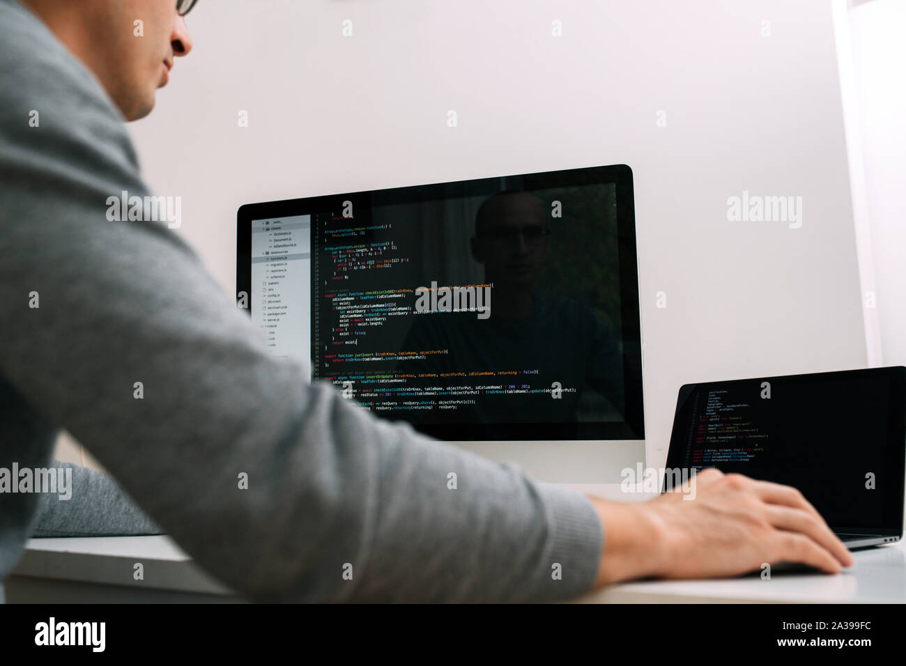 Programmer, working behind the desk, analysing code on the black screen Stock Photo - Alamy