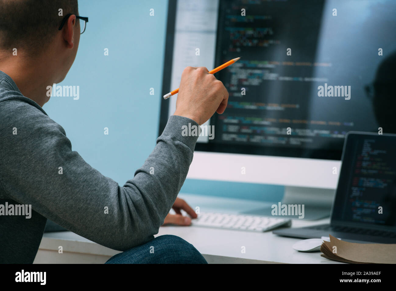 Programmer, working behind the desk, analysing code on the black screen ...