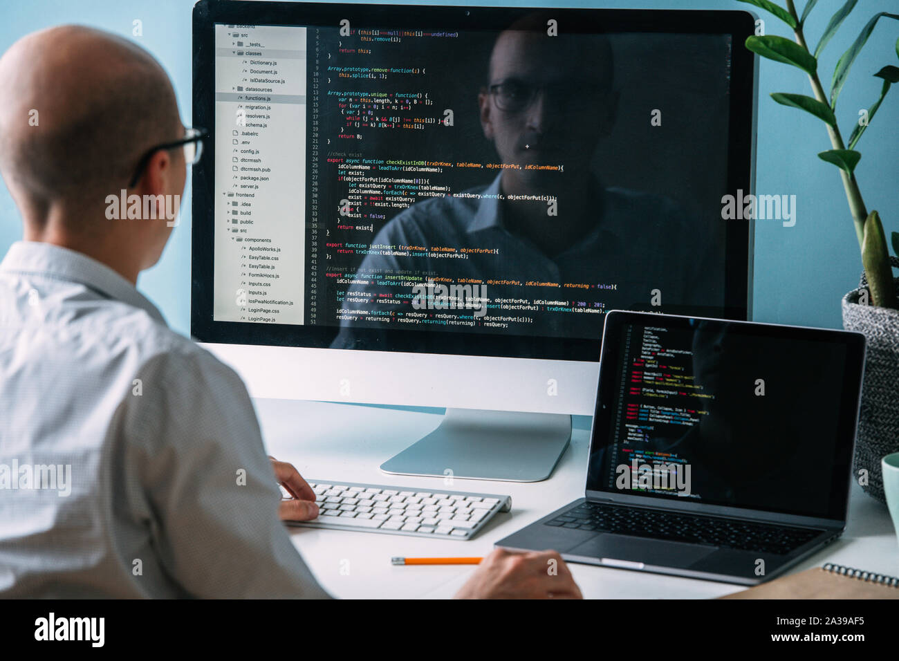 Programmer Working Behind The Desk Analysing Code On The Black Screen