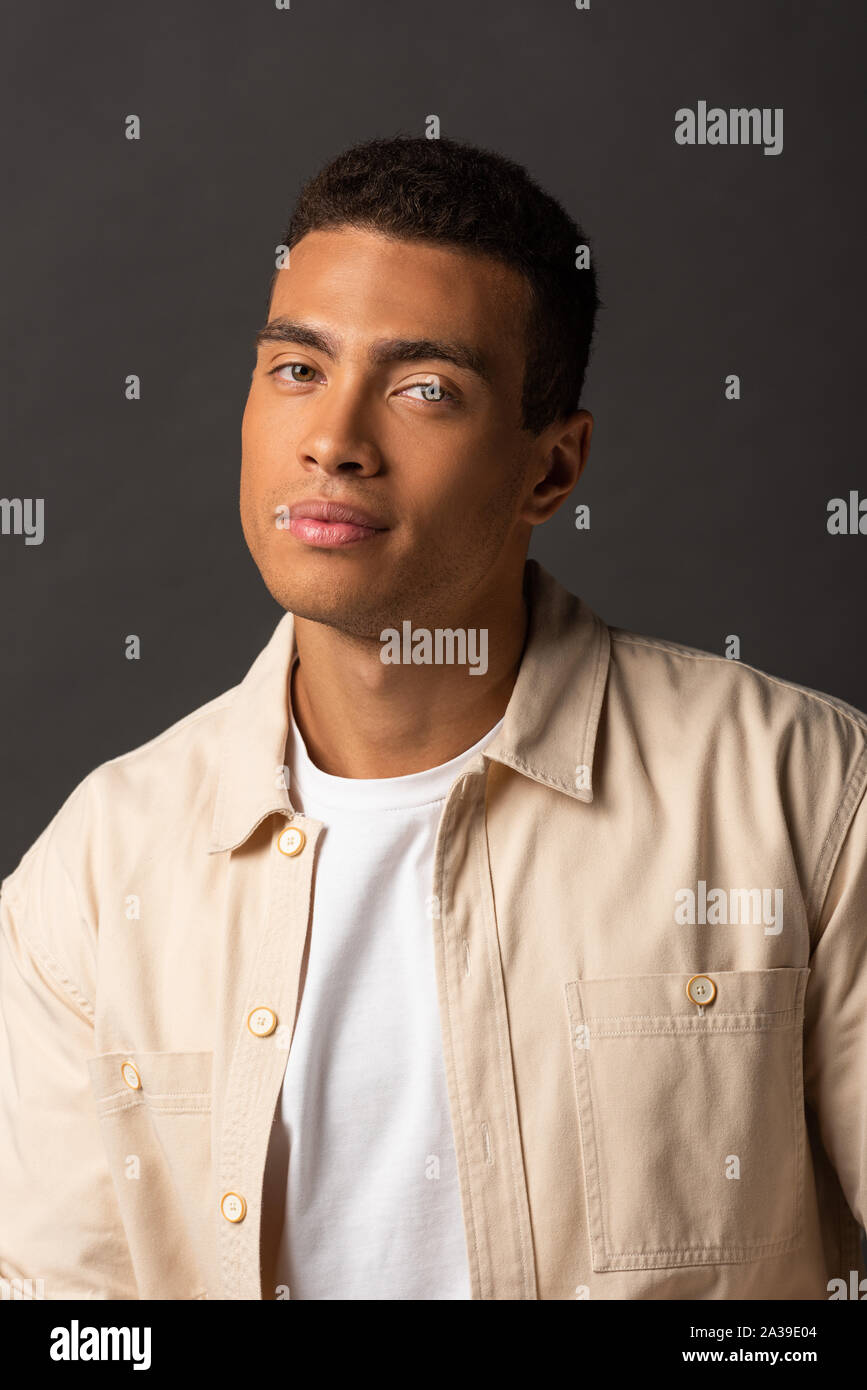 handsome mixed race man in beige shirt on black background Stock Photo ...
