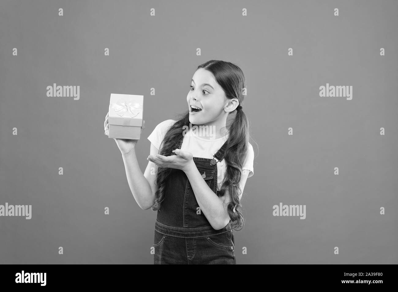 The best present ever. Small child holding birthday present on orange ...