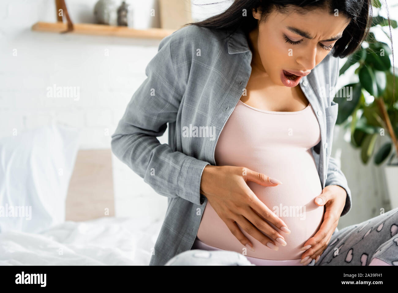 african american pregnant woman in pajamas hugging belly and feeling ...