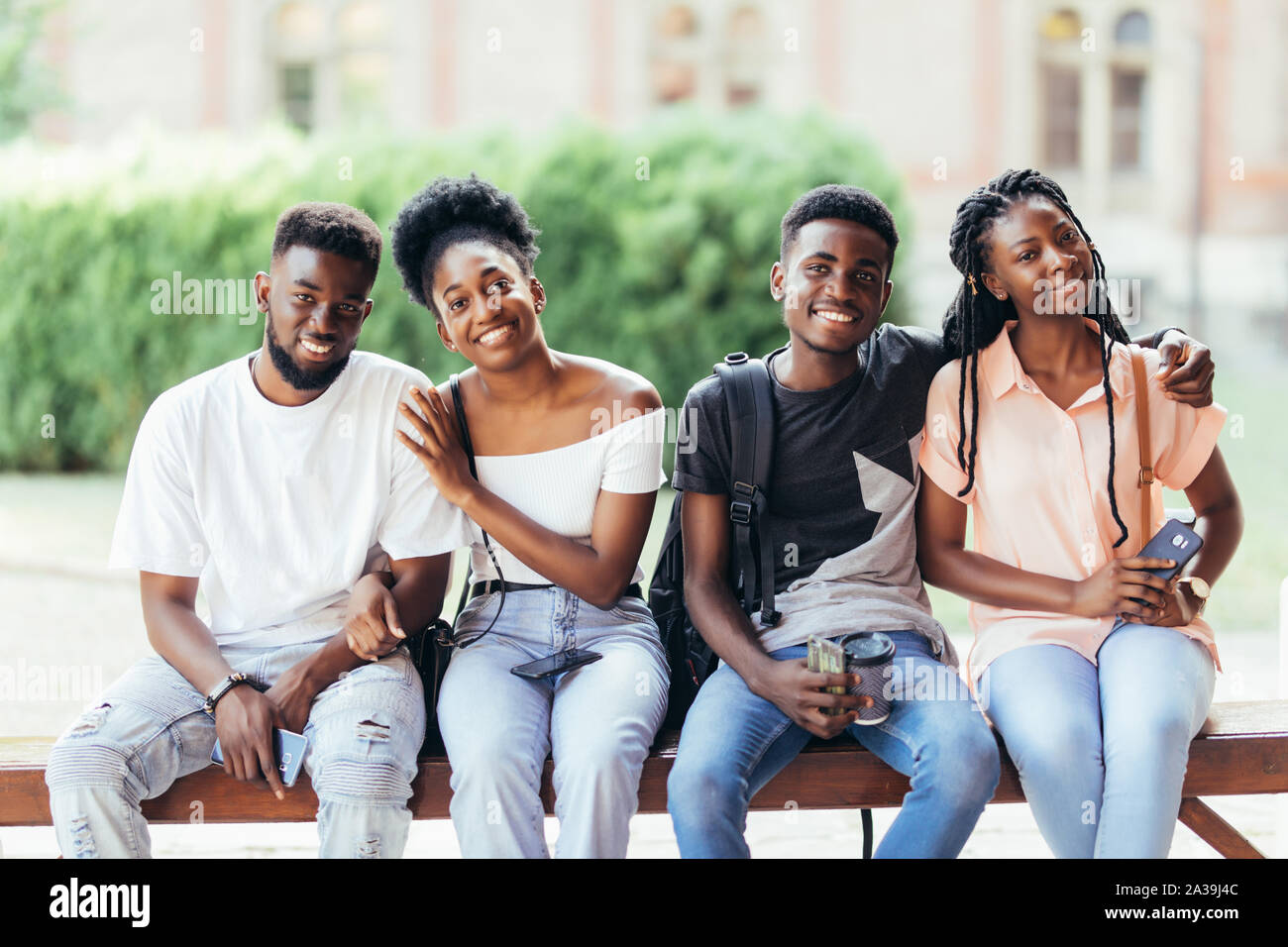 Young students sitting on bench outdoors Stock Photo - Alamy