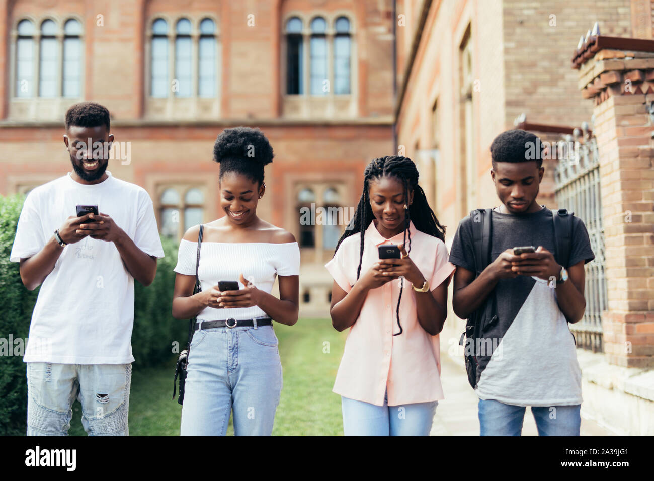 Happy group of students checking smart phones sitting at campus Stock ...