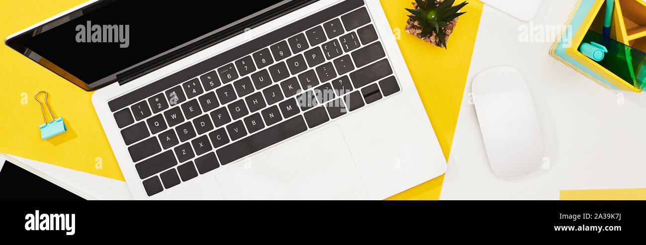 top view of laptop with blank screen and computer mouse on yellow and ...