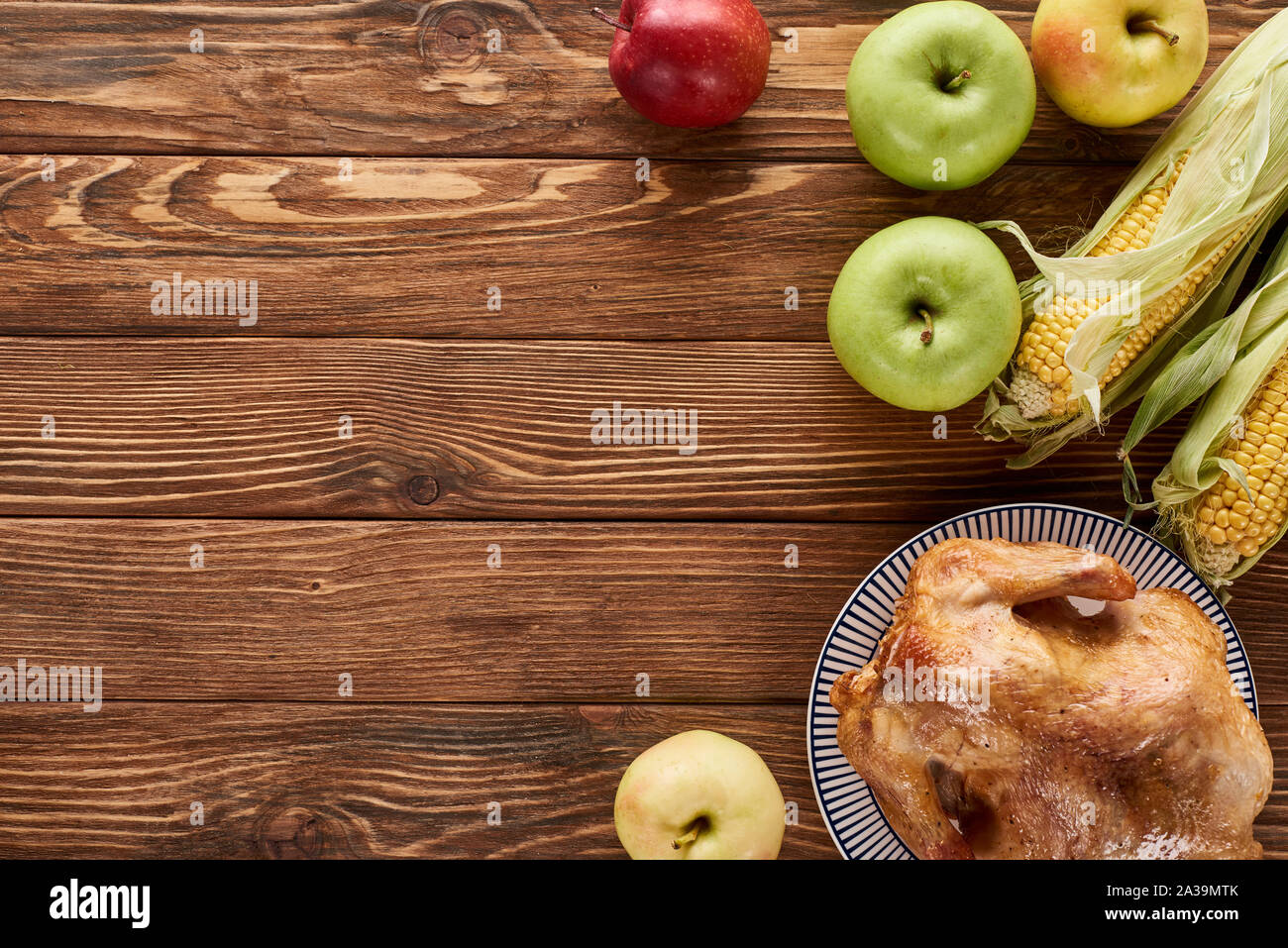 top view of roasted turkey, apples and corn served at wooden table for ...