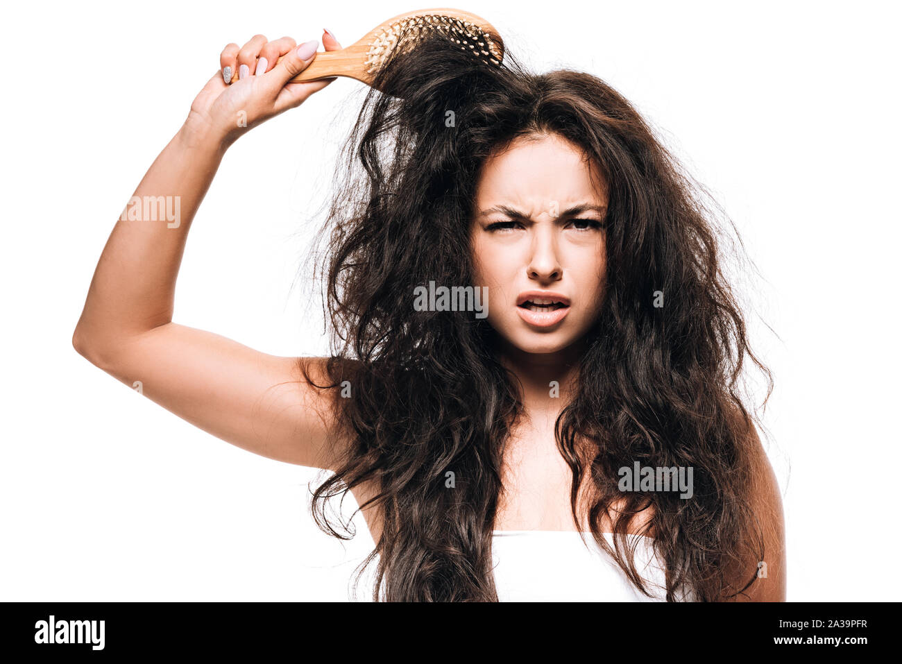 confused brunette woman styling unruly curly hair with hairbrush ...