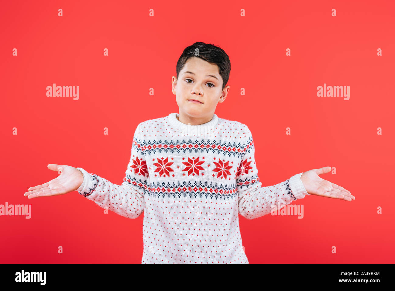 front view of child in sweater showing shrug gesture isolated on red ...