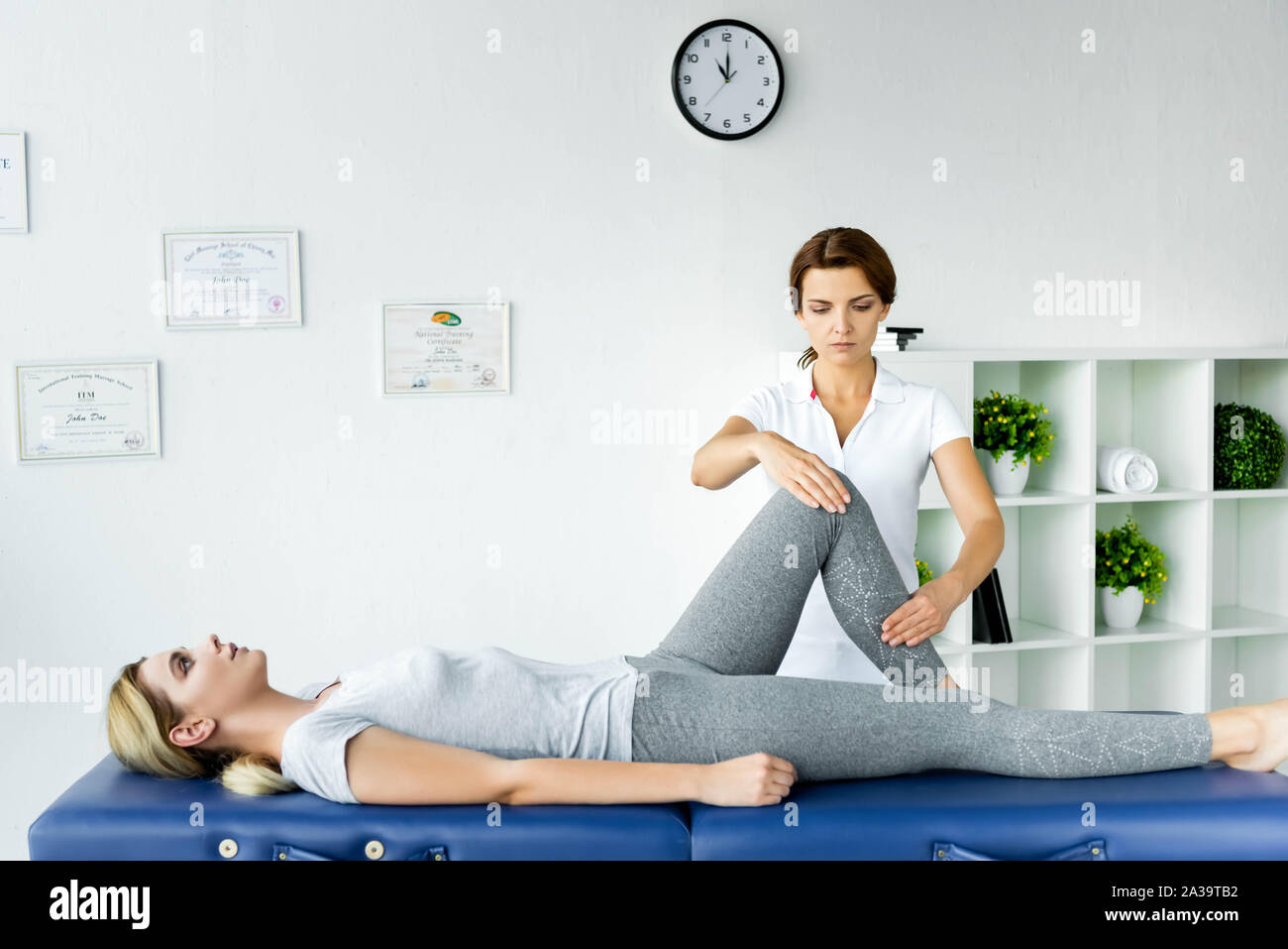 chiropractor touching leg of attractive patient in grey t-shirt Stock ...