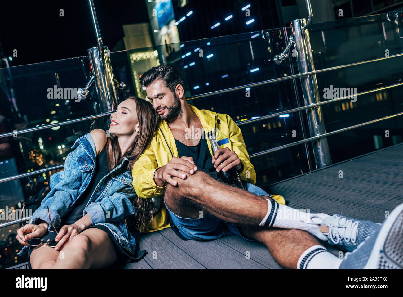 attractive girlfriend lying on shoulder of her boyfriend with bottle in ...