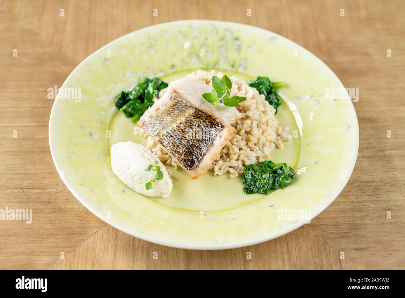 Roasted pike perch or cod fish with bulgur. Dish decorated with a ...
