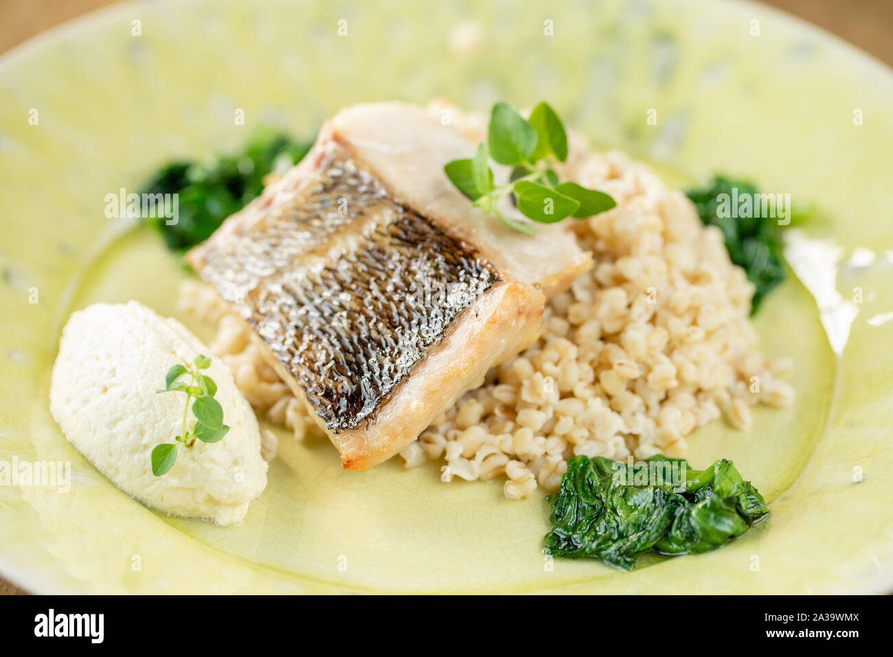 Roasted pike perch or cod fish with bulgur. Dish decorated with a ...