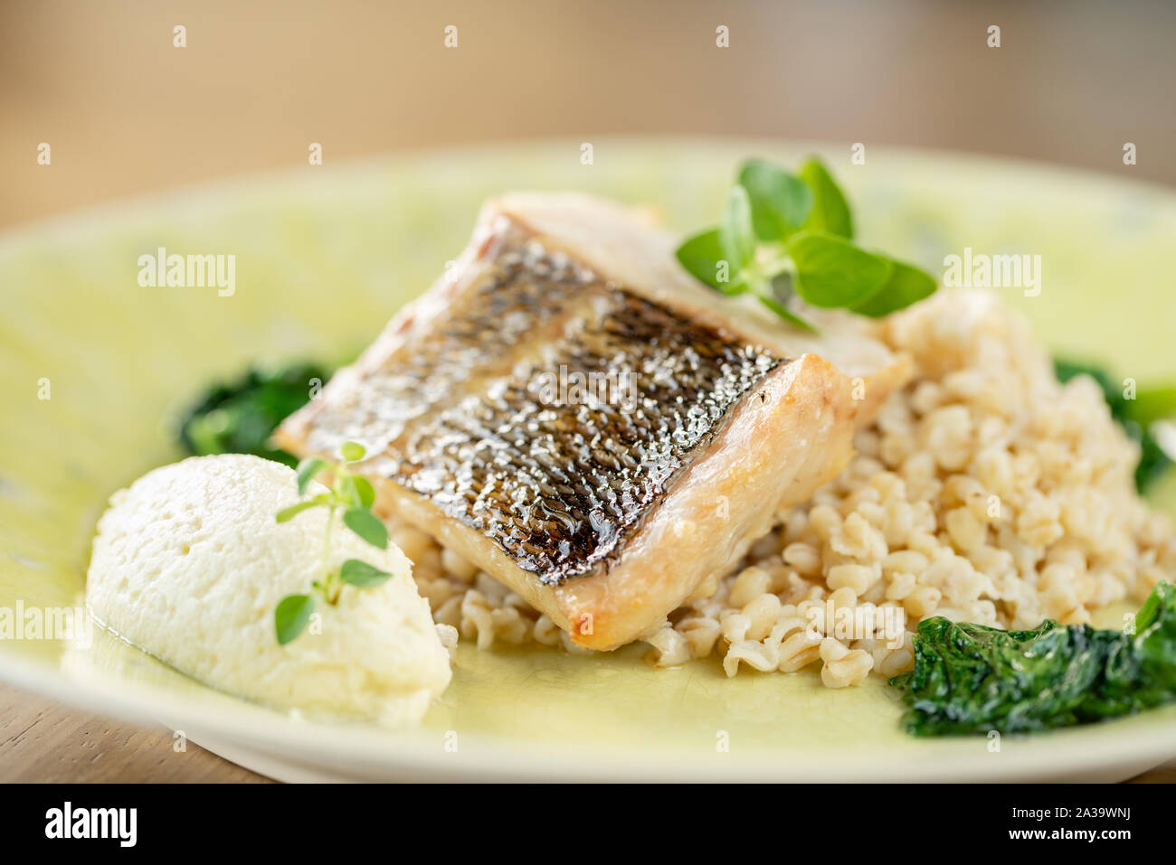 Roasted pike perch or cod fish with bulgur. Dish decorated with a ...