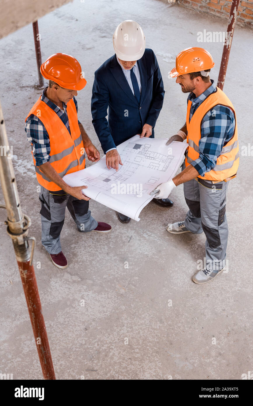 overhead view of constructors and businessman holding blueprint Stock ...