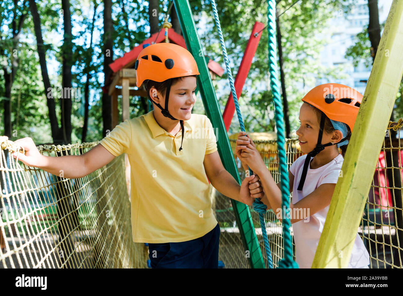 happy kid in helmet looking at adorable boy in adventure park Stock ...