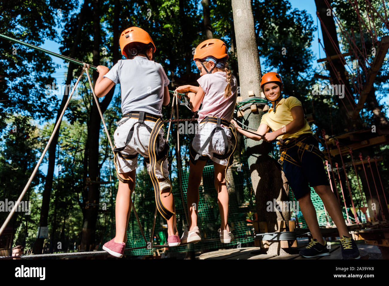 multicultural boys in helmets near friend on high rope trail Stock ...