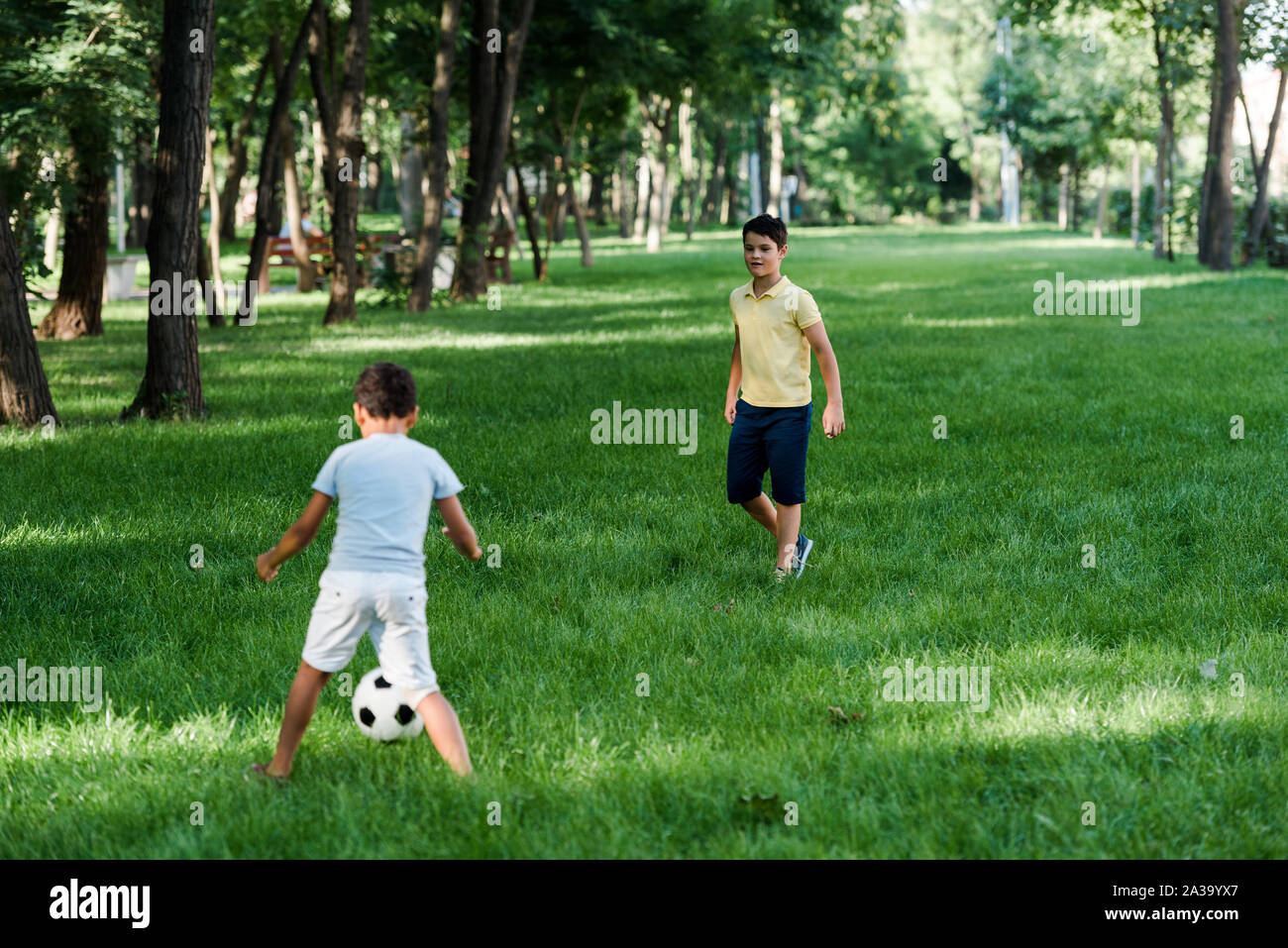 cute multicultural boys playing football on grass Stock Photo - Alamy