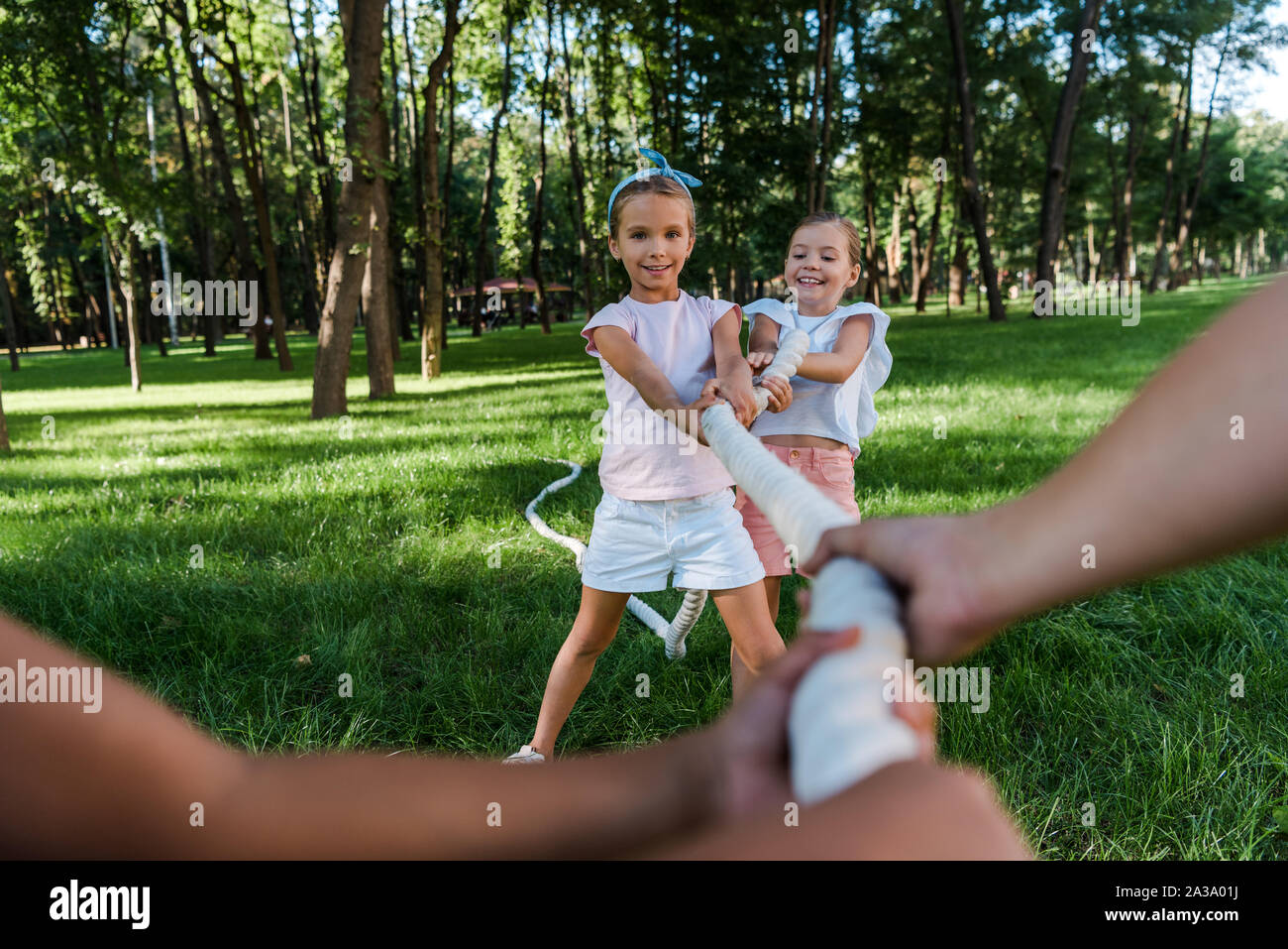 selective focus of cheerful multicultural children competing in tug of ...