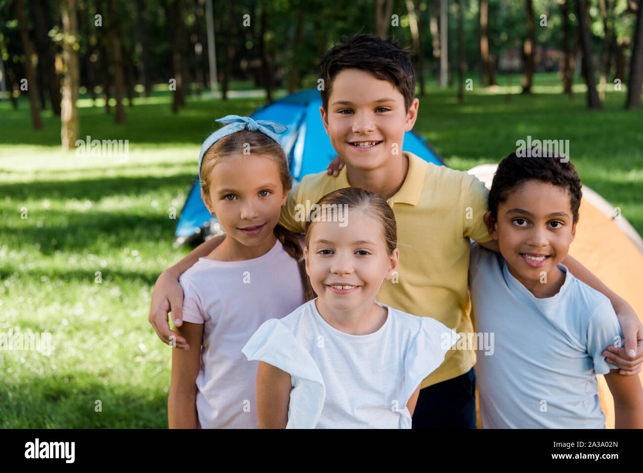 happy multicultural kids smiling near camps in park Stock Photo - Alamy
