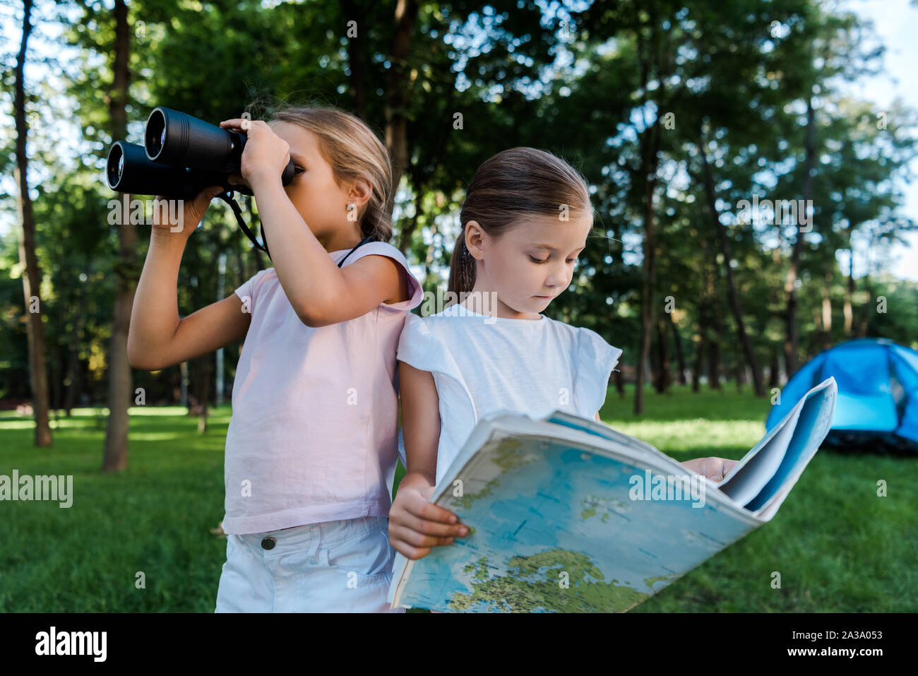cute kid holding map near friend looking through binoculars Stock Photo ...