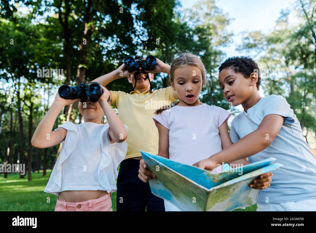 surprised kid looking at map with african american boy near friends ...