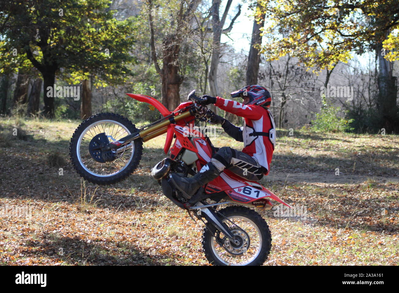 Boy doing a wheelie with the front wheel in the air, outdoors in a ...