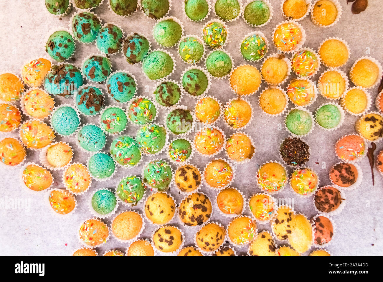 Tray with small muffins with colored topping Stock Photo - Alamy