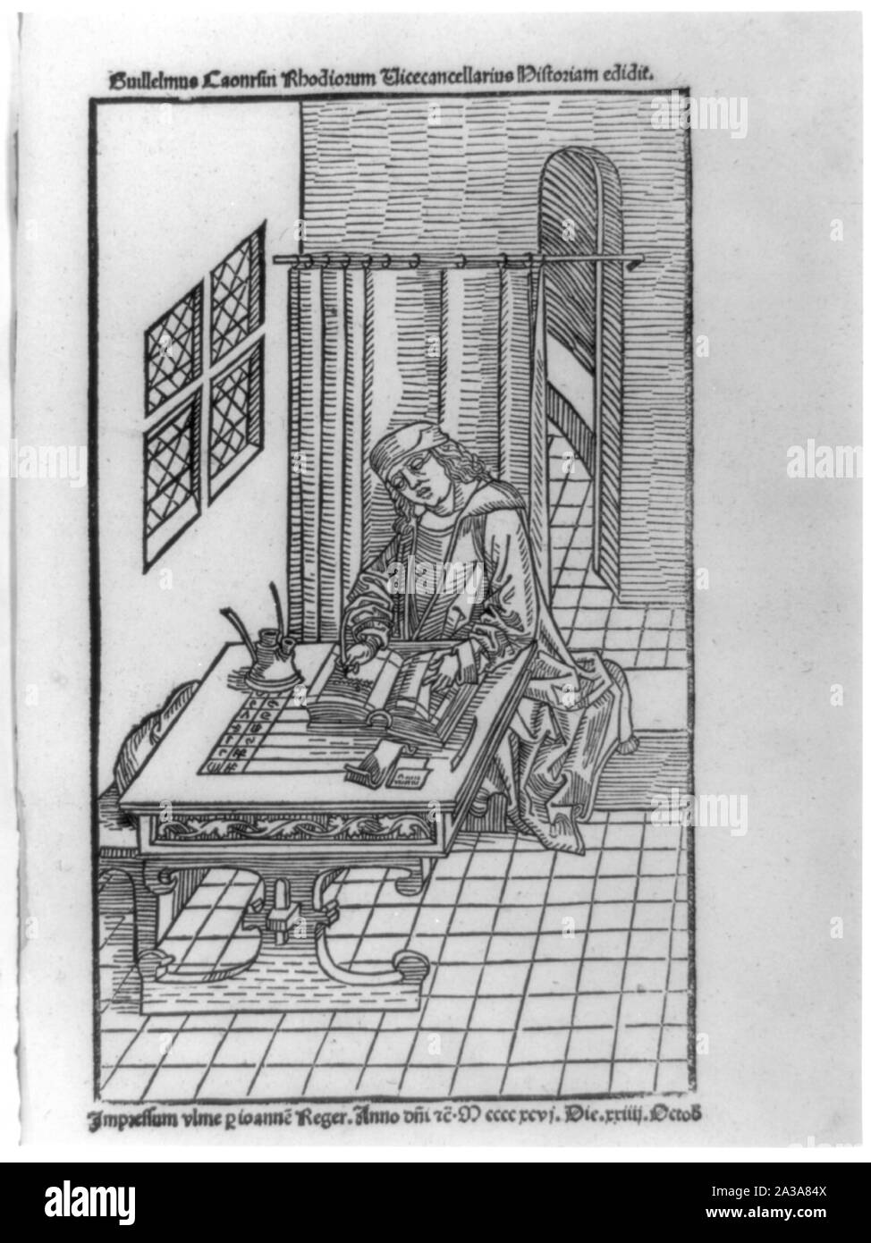 Seated figure writing at desk Stock Photo - Alamy