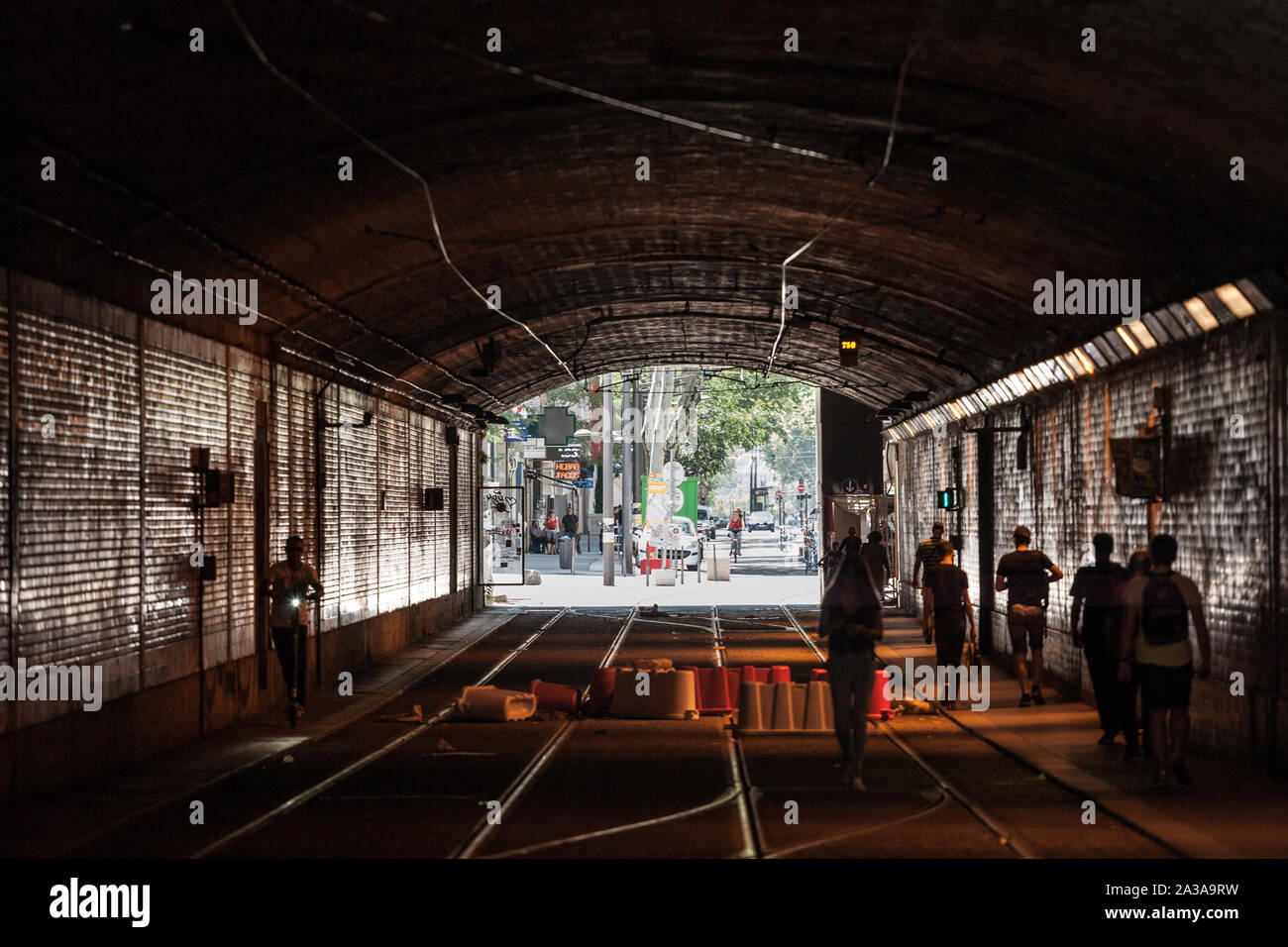 LYON, FRANCE - JULY 14, 2019: People walking in a dark tunnel towards ...