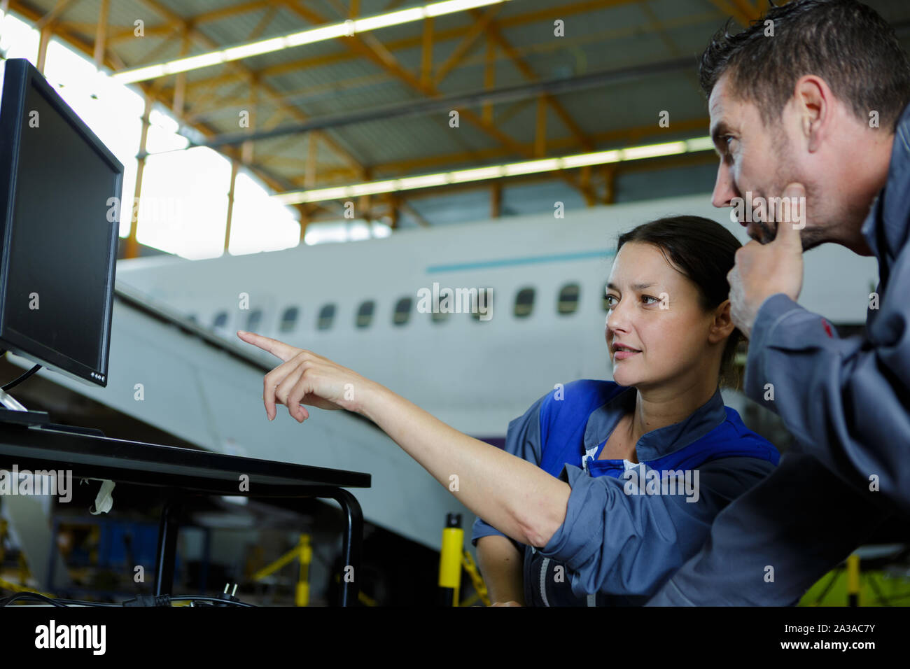 engineers looking at computer screen in aircraft hangar Stock Photo - Alamy