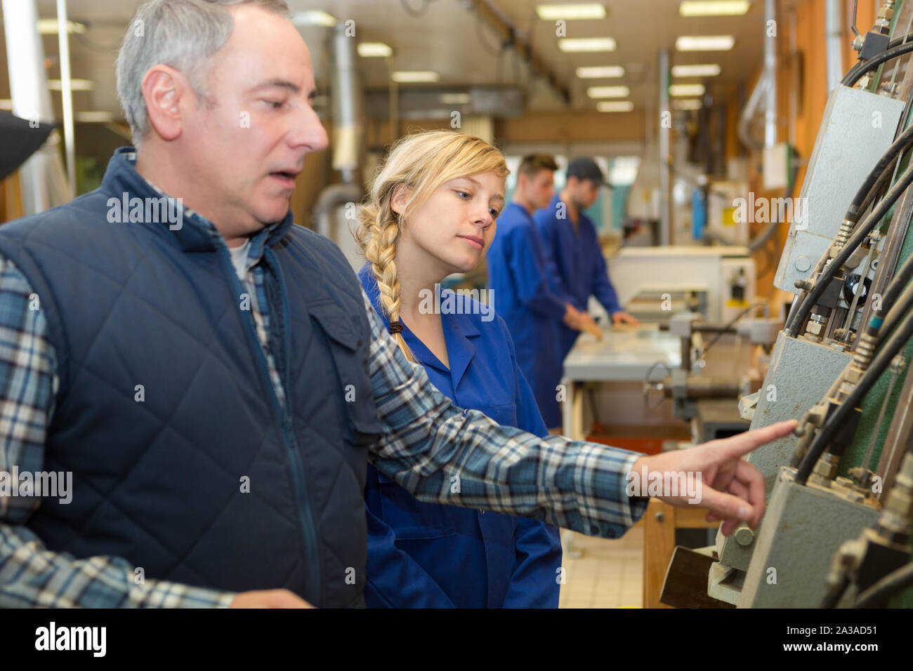 craftsman and female apprentice processing wood with machine Stock ...