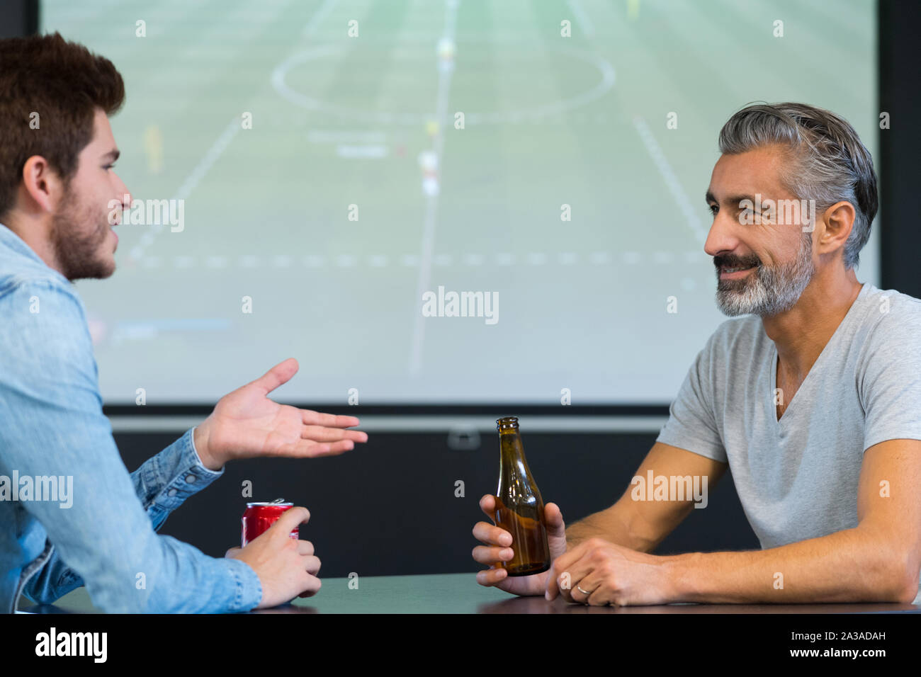 two men in bar watching football and drinking beer Stock Photo - Alamy