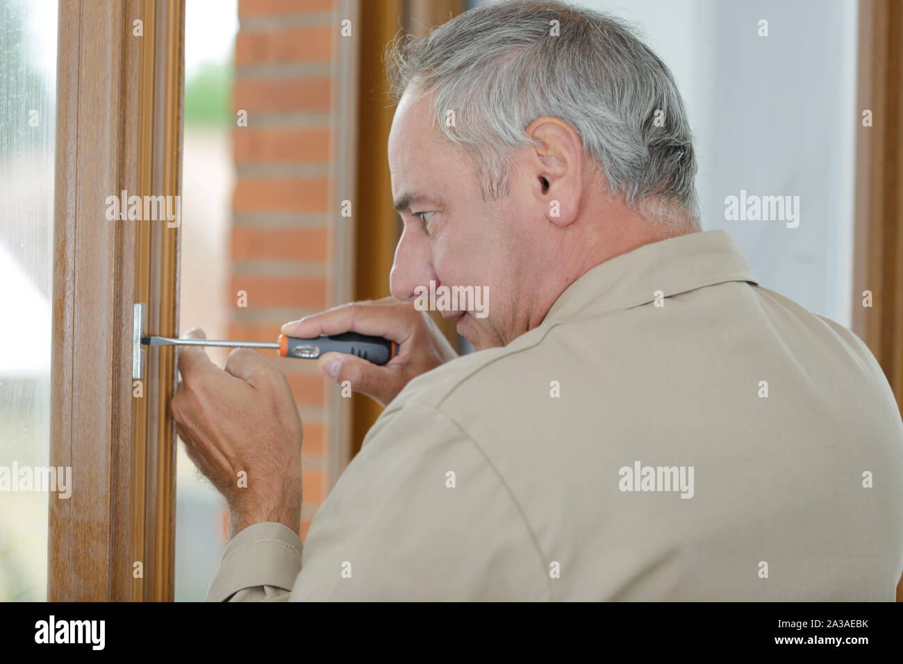 mature man using screwdriver on window Stock Photo - Alamy