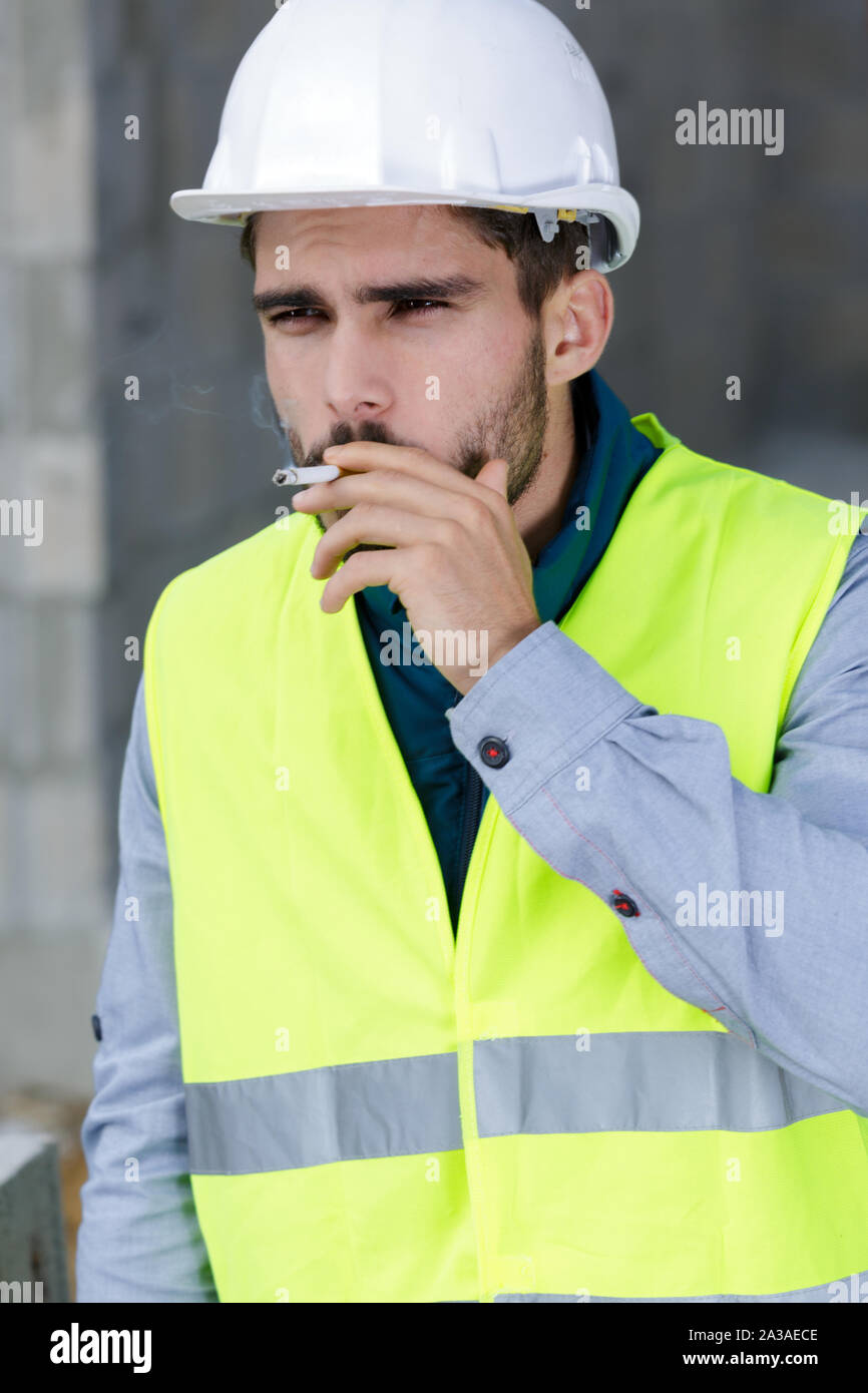 happy builder smoking cigarette in construction site Stock Photo - Alamy
