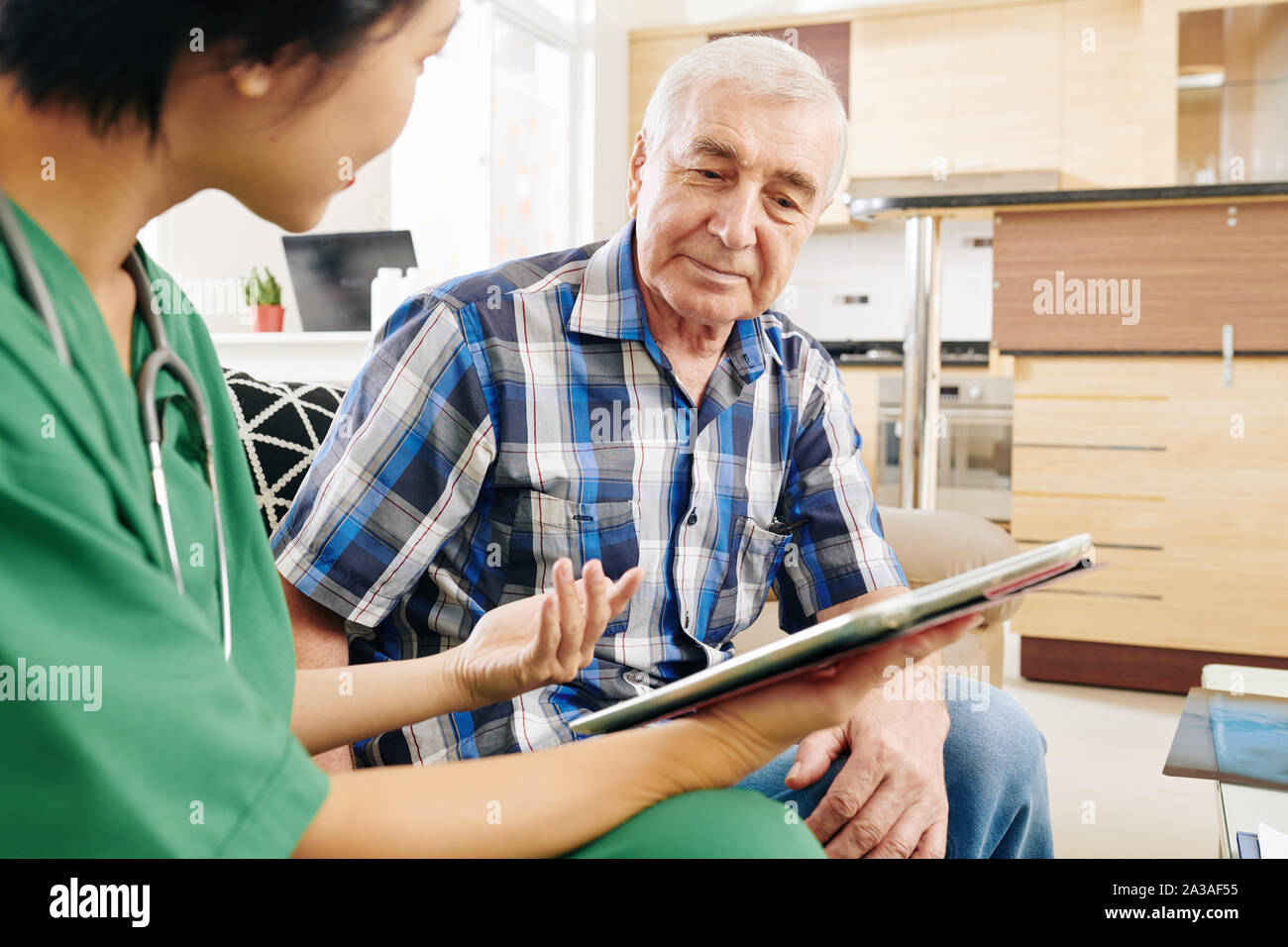 Nurse visiting old man at his apartment and explaining how to use ...