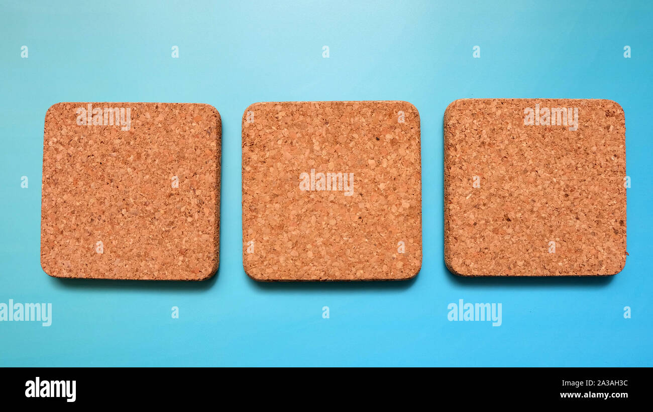 3 square cork tiles arrange in a row next to each other, with a blue ...