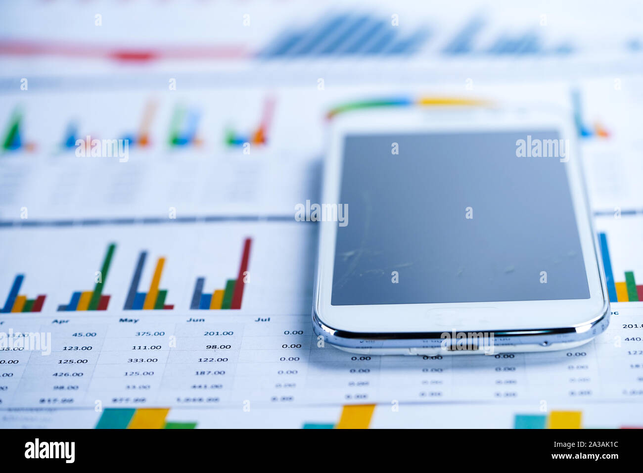 Mobile phone on charts graphs spreadsheet paper. Financial development ...
