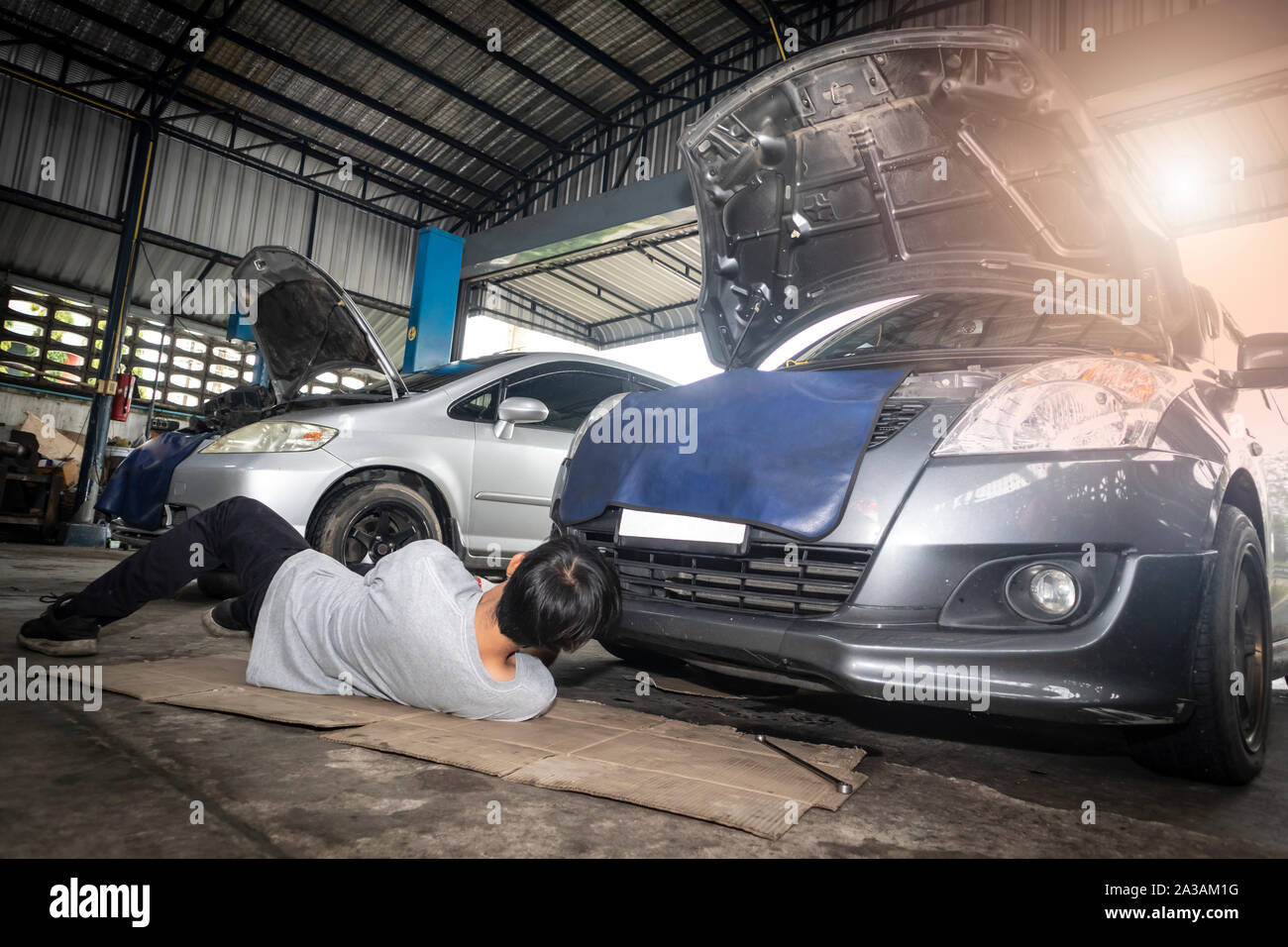 Mechanic lying down and working under car at the garage. Mechanics ...