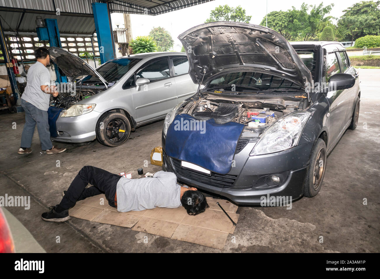 Mechanic lying down and working under car at the garage. Mechanics ...