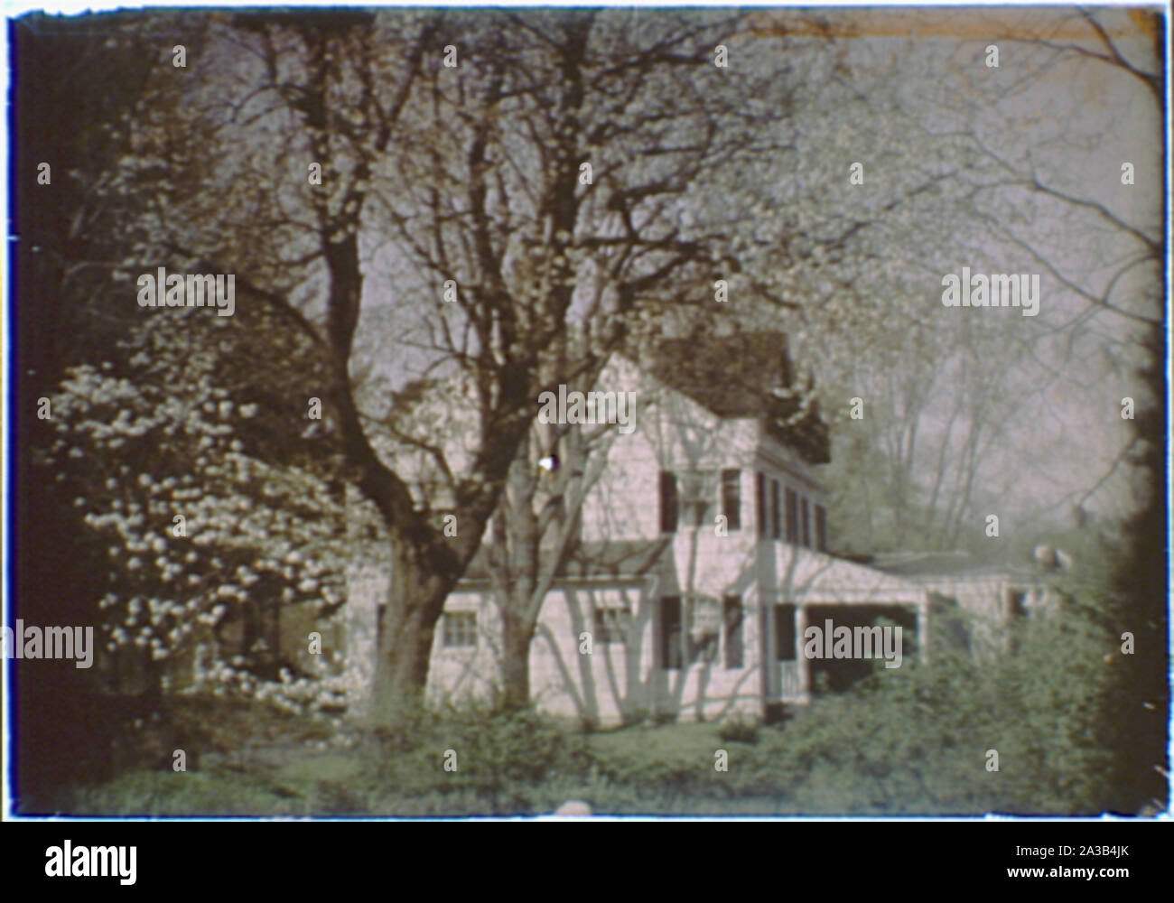 Side view of a two-story house with white planking and black shutters ...